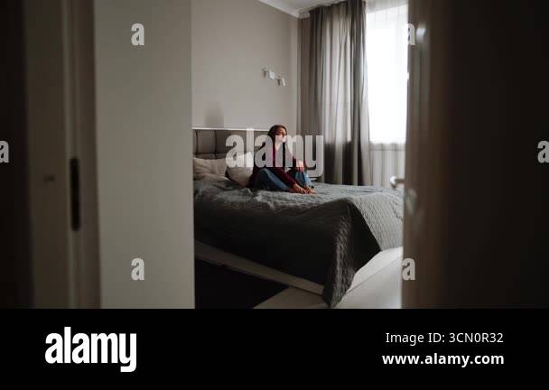 Woman relaxing in a bedroom while watching television in the evening ...