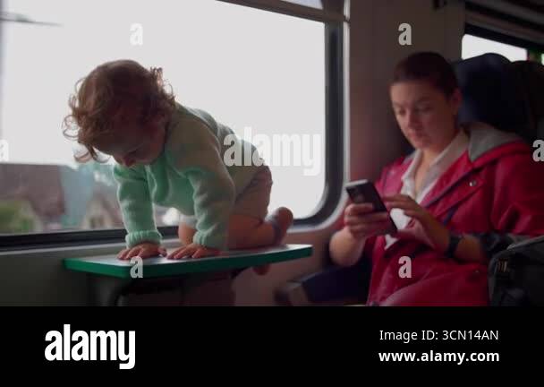 Child kneeling on train table looking out window while woman next to ...