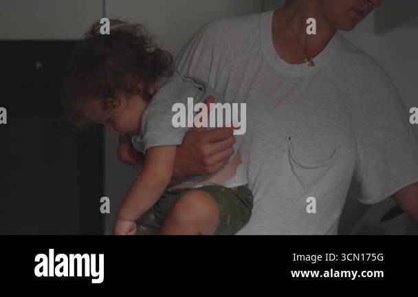 Mother carrying toddler on hip while multitasking in kitchen, balancing ...