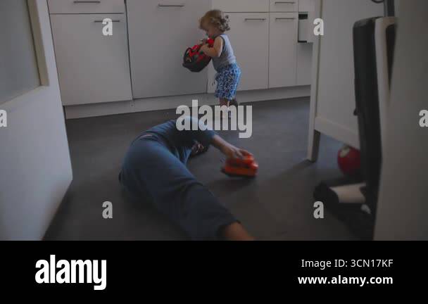 Toddler holding helmet while older sibling plays with toy car on ...