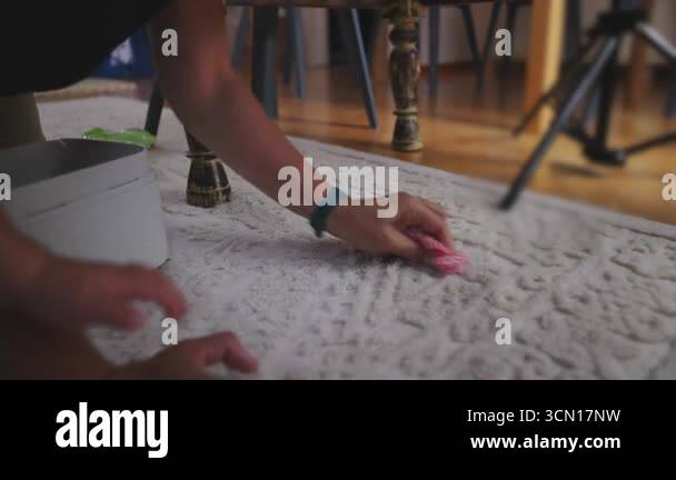 Mother scrubbing carpet stain with pink cloth while toddler plays ...