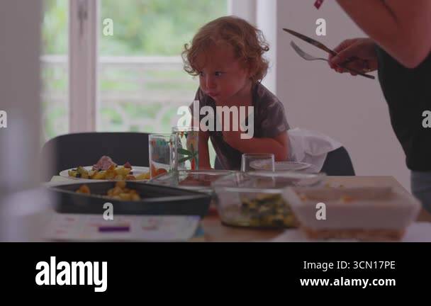 Mother grabbing food from serving dishes before sitting down for family ...