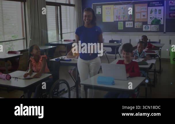 Teacher tapping tablet, walking between desks in classroom, digital ...
