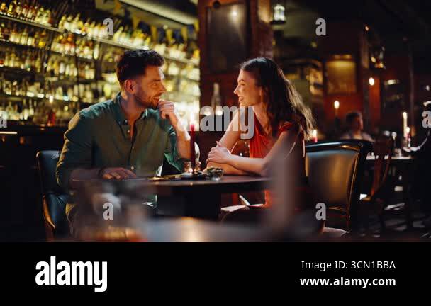 Happy lovers talking in pub sitting in cozy night atmosphere. Smiling ...
