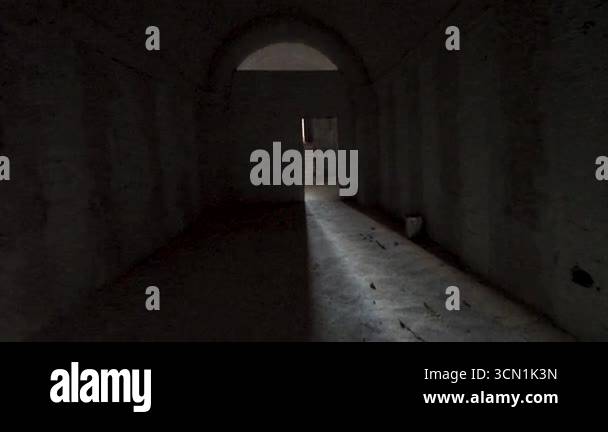A dimly lit corridor leading to a staircase, with shadows and textured ...