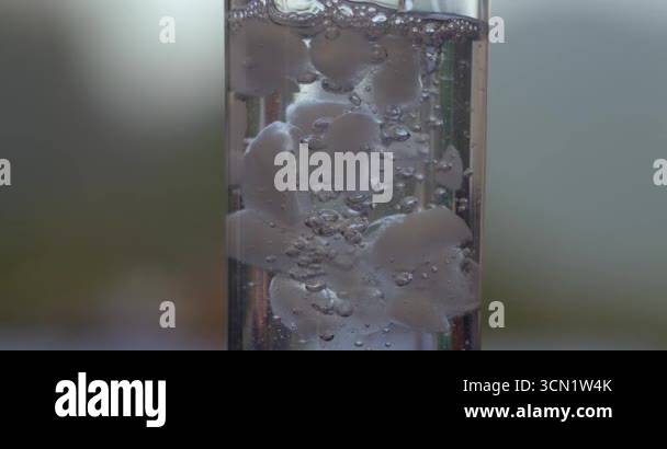 Glass filled with ice cubes and still water, close up showing bubbles ...