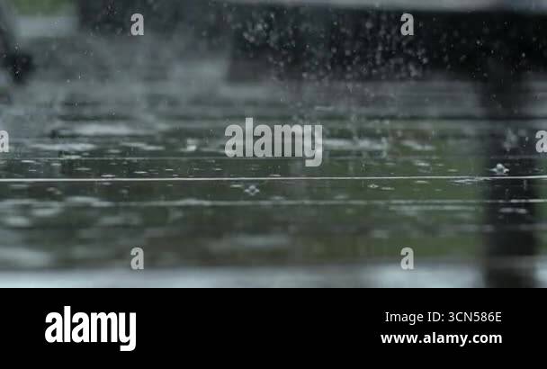Rain drops creating dramatic water bursts on reflective floorboards ...