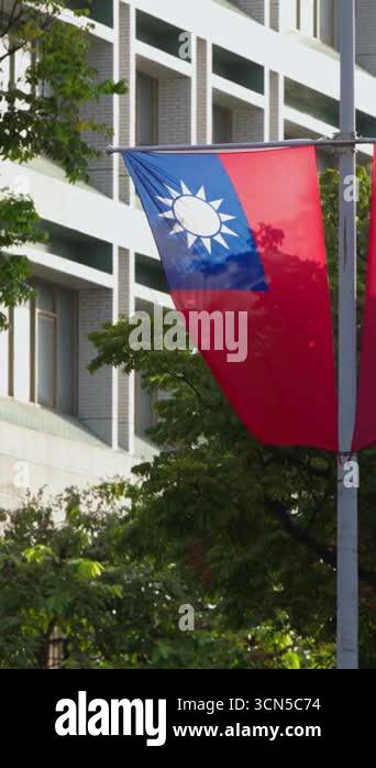 Vertical Slow motion of Taiwan flag with a green tree and city building ...