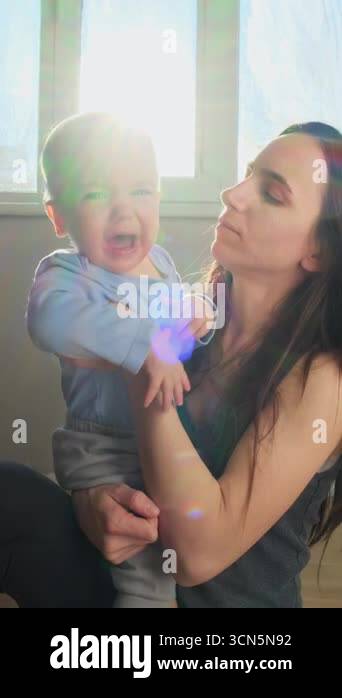 Mother calms the child in teeth pain and hugs her crying baby toddler ...