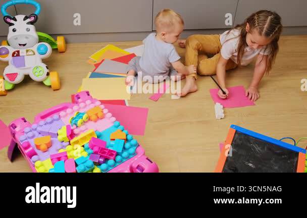 Two cute sibling children drawing on papers in kitchen room. Elder ...