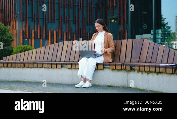 Caucasian girl sitting on bench in casual clothes, with her arms behind ...