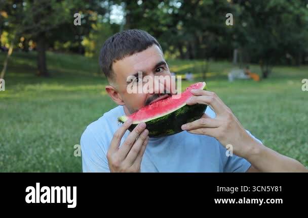 handsome guy eating watermelon on green grass Stock Video Footage - Alamy