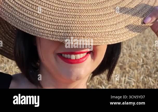 Girl lifts wide-brimmed hat and shows her charming smile close-up ...