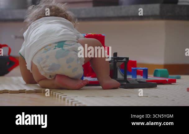 Toddler crawling on floor reaching for toy garage and cars, playful ...