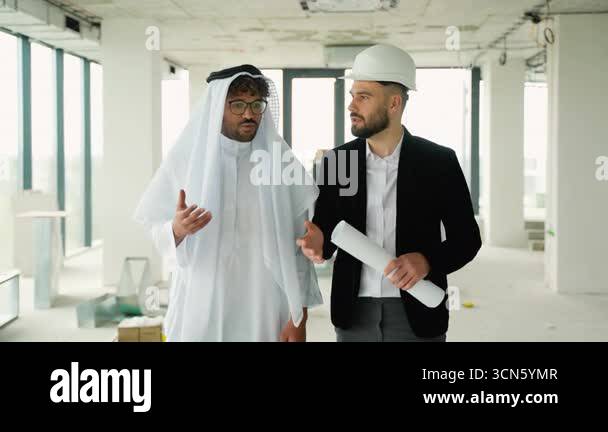 Arab businessman in traditional clothing shows a building under ...