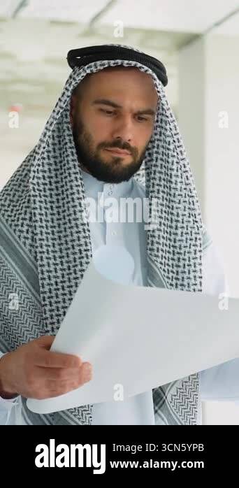 Experienced arab architect in traditional attire meticulously reviewing ...