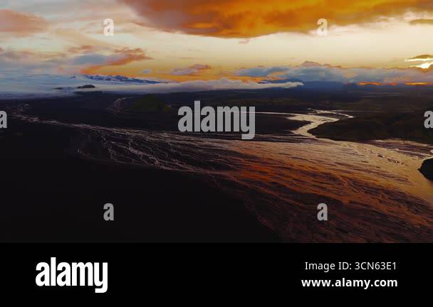 Aerial view of Maelifell volcano with a winding river reflecting sunset ...