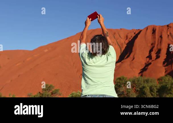 A woman stands in front of the iconic Uluru in Australia's Northern ...