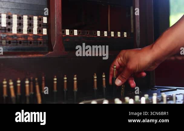 A close-up of a hand connecting a red cable into a vintage telephone switchboard. The retro ...