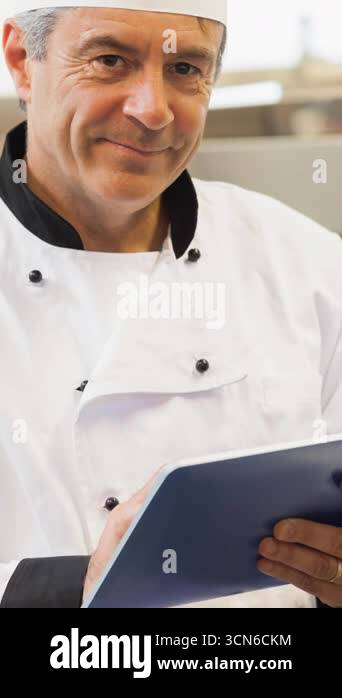 Smiling caucasian male chef wearing apron using tablet in professional ...