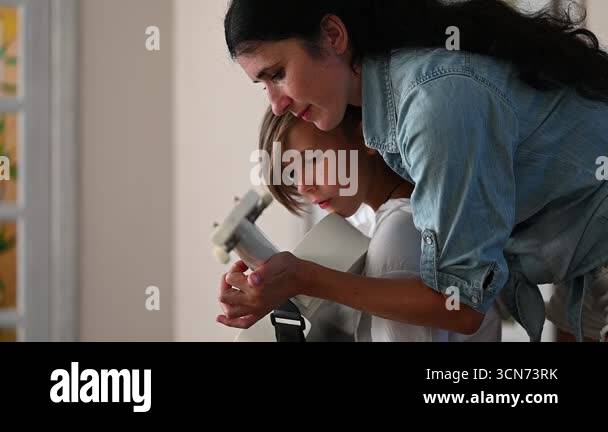 A mother gently guides her child during a creative project, showcasing ...