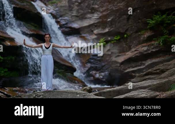 Beautiful young woman performing slow tai chi movements near a ...
