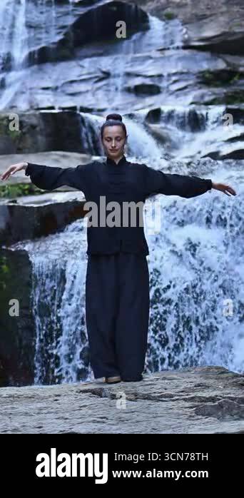 Beautiful young woman performing slow tai chi movements or meditating ...