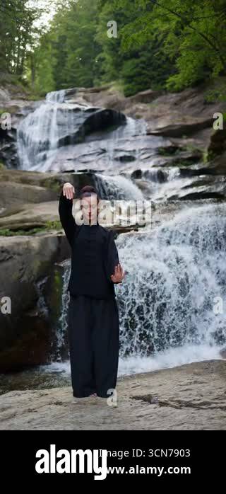 Beautiful young woman performing slow tai chi movements or meditating ...