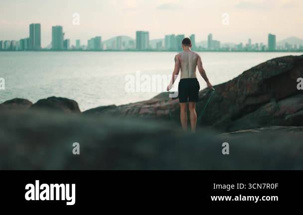 Man jumping rope at mountain cliff on rocks during sunset workout, male ...