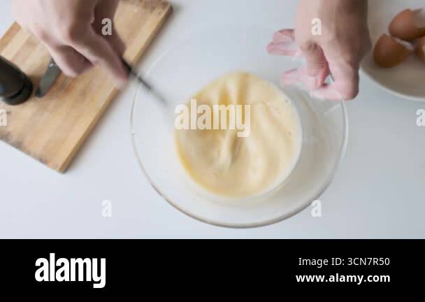 Man whisking egg and milk mixture in glass bowl in home kitchen during ...