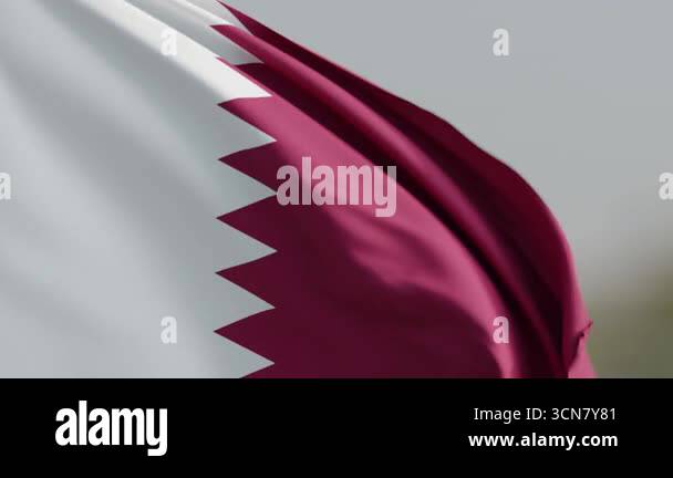 The national flag of Qatar gracefully waves in the wind, showcasing its ...