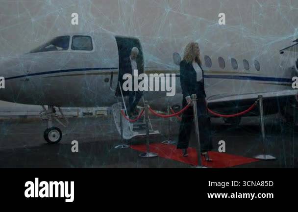 Executive descending jet stairs holding phone and leading associate ...