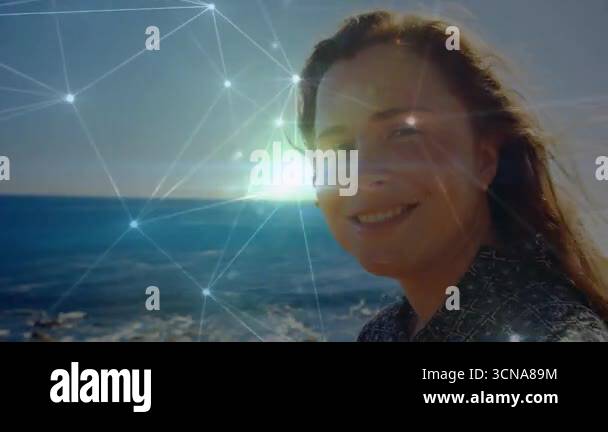 Woman lowering gaze and closing eyes on shoreline while tech overlay reacting to sunlight ...