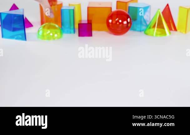 Vibrant 3D geometric shapes roll across a white surface, demonstrating ...
