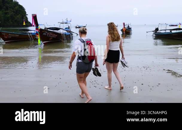 Two people approach boats on Ao Nang Beach Stock Video Footage - Alamy