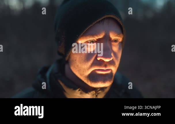 Close-up portrait of a man at night in the forest, his face illuminated ...