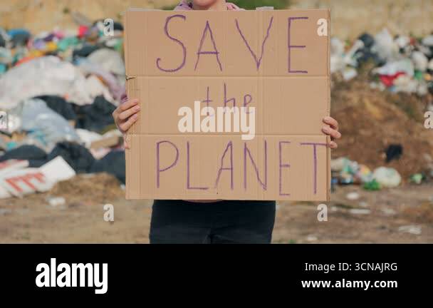 A female activist holds a cardboard sign reading SAVE THE PLANET in ...