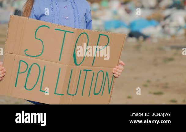 A young activist holds a handmade cardboard sign that reads Stop ...