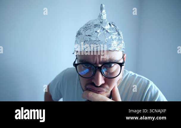 A man with glasses displays a mix of humor and paranoia, wearing a ...