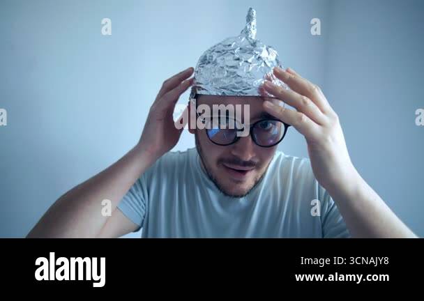 A man wearing an aluminum tinfoil hat shows a bewildered expression ...