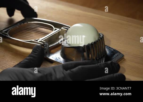 Use an egg slicer to cut a boiled chicken egg, close up. Cutting eggs ...