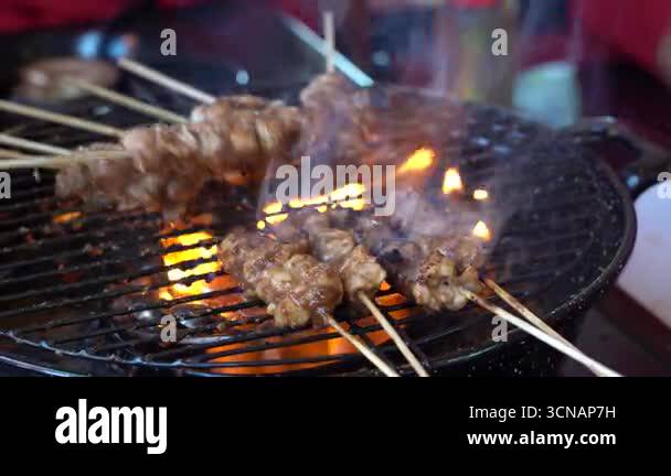 Street vendor sells grilled chicken meat at street food market in ...