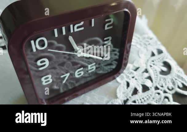 A close-up shot shows a brown vintage-style analog alarm clock with a ...