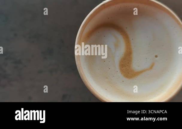 Macro top-down shot slowly zooms out from a disposable paper cup of ...