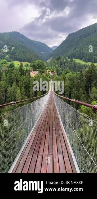 Suspension bridge spanning valley, picturesque mountain village ...