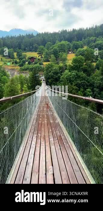 Suspension bridge spanning valley, picturesque mountain village ...