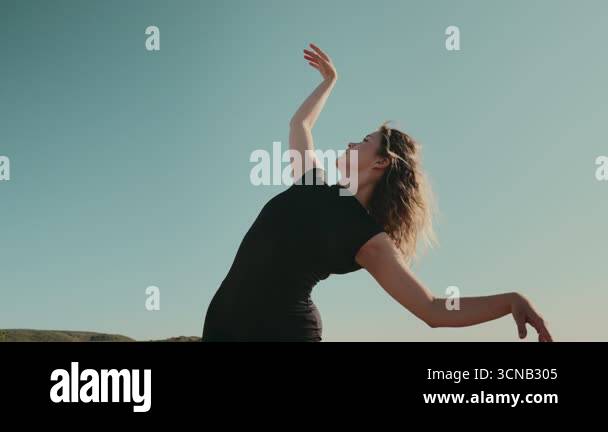 Elegant dancer gracefully moving outdoors with arm extended against a ...