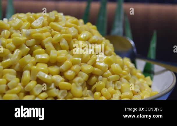 Scooping up sweet canned corn with a spoon. corn on a plate canned ...