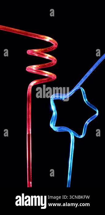 Vibrant blue and red straws spinning and twirling against a black ...