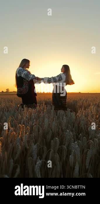Girls are dancing in the field at sunset. Two girls are dancing holding ...